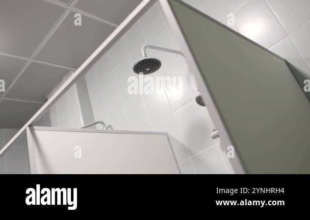 Shower cabin equipped with spraying heads and shelf in tiled public ...