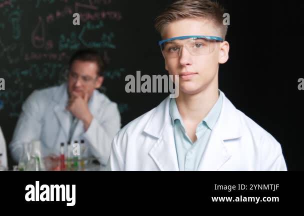Smart student looking at camera while diverse group doing experiment ...