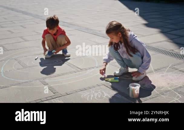 Two kids drawing crayons at sunny street. Cute children sitting at ...