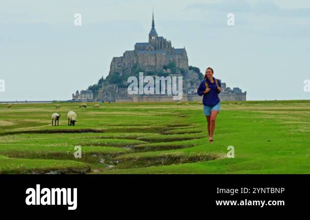 A female with a backpack visits the Mont Saint Michel castle while ...