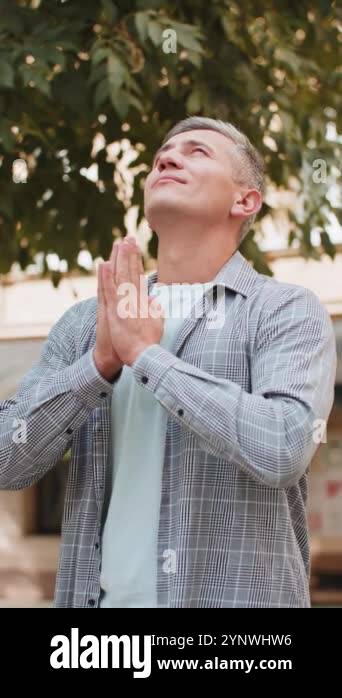 Caucasian mature man tourist praying with closed eyes to God asking for ...