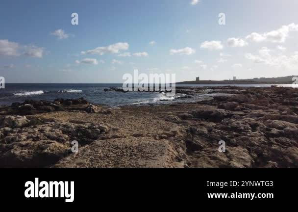Rocky coast of Malta and Ghallis Tower, Salina small watch tower in the ...