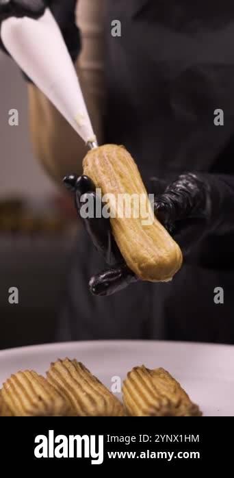 pastry bag with cream. Confectioner makes eclairs in a bakery. eclair ...