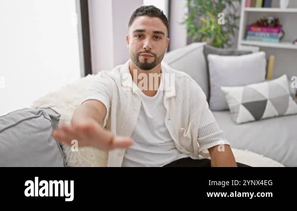 Serious young arab man making a stern stop gesture with his palm indoors, expressing caution and ...