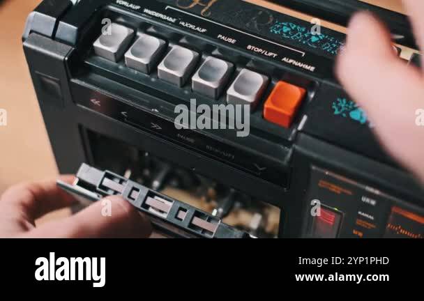 A cassette tape is inserted into a vintage player and the play button ...