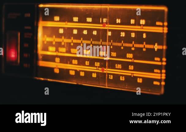 Extreme close-up of a vintage radio dial bathed in a warm orange glow ...