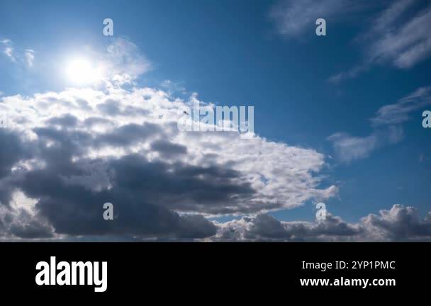 Timelapse of fluffy white clouds moving across a blue sky. The sun ...