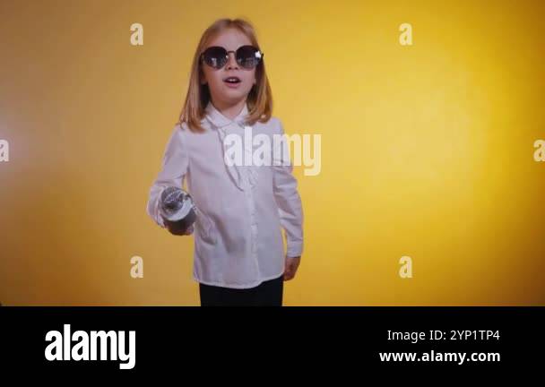A young girl, sunglasses perched on her nose, belts out a song with a ...
