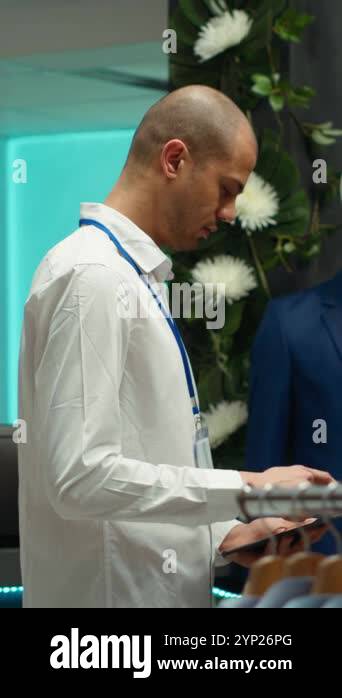 Vertical Video Store employee arranging new collection of clothes on ...