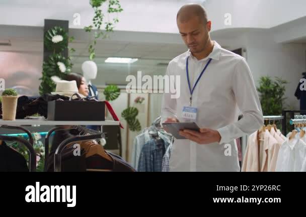 Middle eastern clothing store employee verifying merchandise stock on ...