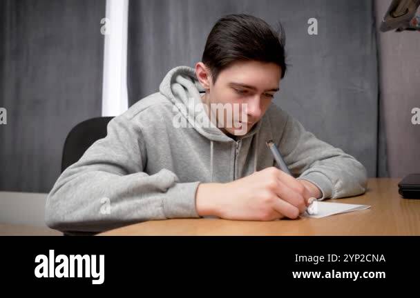 Teenager writes letter in handwriting. Adolescent boy writes ...