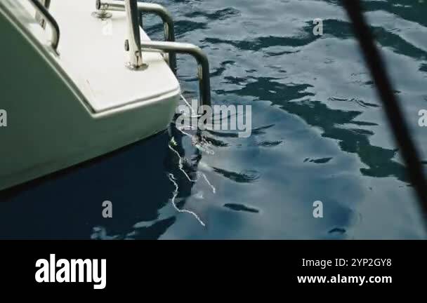 Boat ladder partially submerged in the deep blue ocean on a rainy day ...