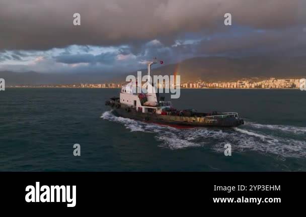 Watch a tugboat head to port after a mission at sunset, with a vibrant ...