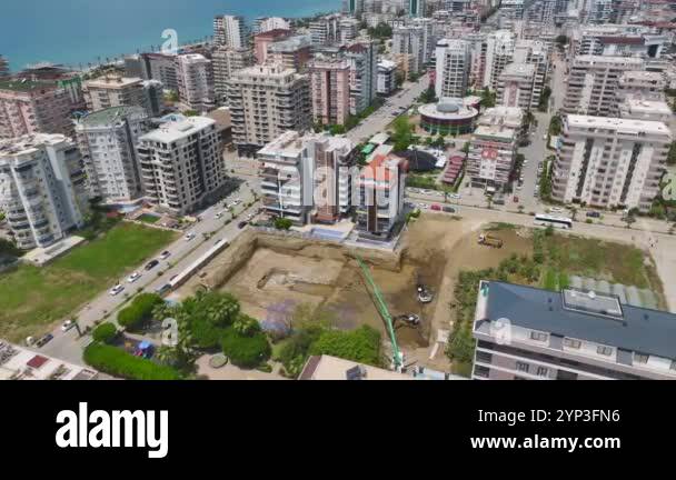 Watch as heavy machines pour concrete into a deep pit, forming the ...