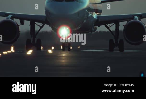 The wheels of a passenger plane travel along an illuminated runway ...