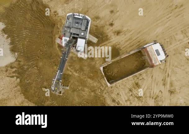 Fly over a construction site where excavators and trucks are busy ...