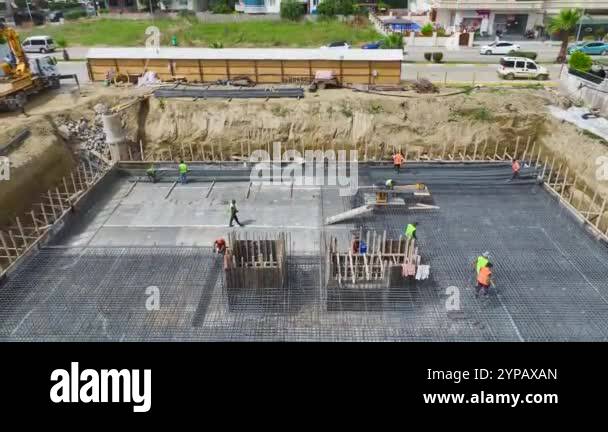See construction workers laying the foundation and bending rebar for ...