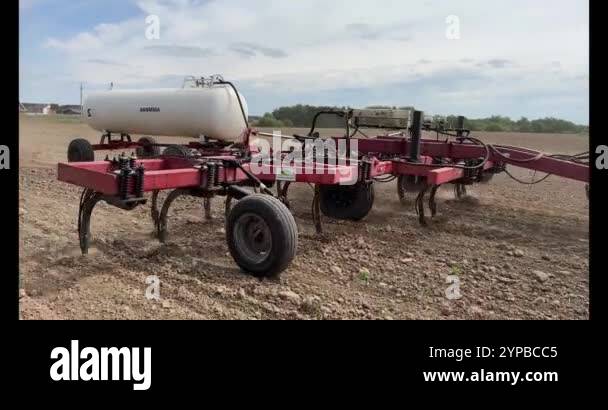 Green tractor is pulling a white tank behind it. The tractor is in a ...