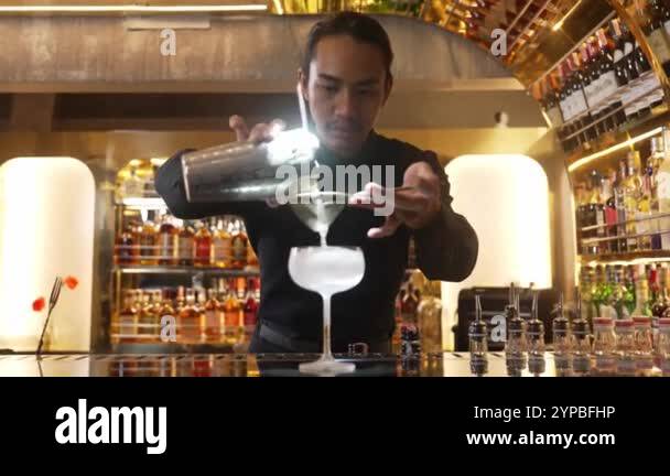 Smart Asian bartender using strainer mixed vodka cocktail at luxurious ...