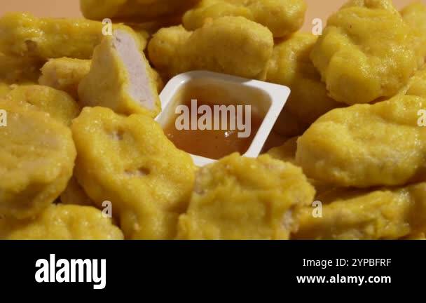 Rotating A pile of yellow chicken nuggets with a small white container ...