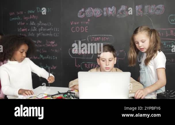 Caucasian boy using laptop programing engineering code and writing program while group of ...