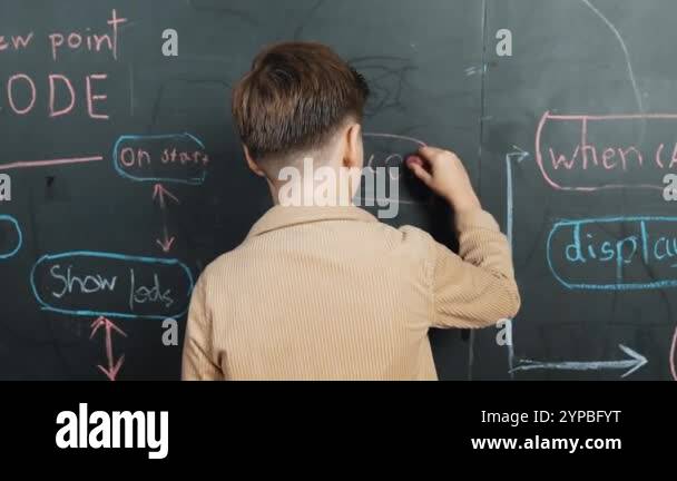 Smart boy writing engineering prompt on blackboard while turn around ...