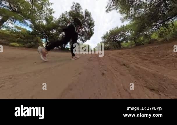 A dynamic slow-motion view shows a woman running on a sandy trail with ...