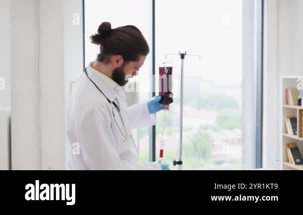 Male doctor with beard, wearing lab coat and gloves, prepares blood ...