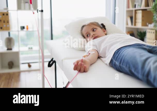 Young Caucasian girl lies on medical couch receiving blood transfusion ...