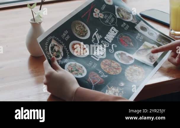 Close-up shot of unrecognizable woman holding menu with images of ...