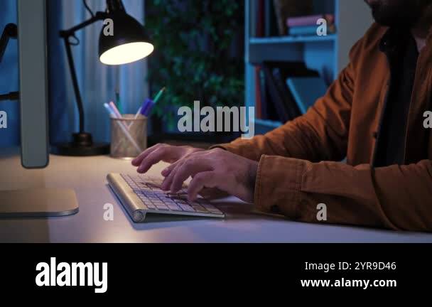 Office employee working overtime. Young business man sitting at desk working late at night in ...