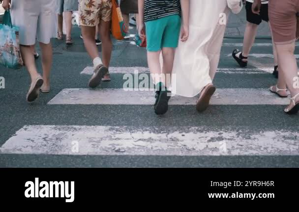 Peoples legs walking on a crosswalk, busy urban street scene, summer ...