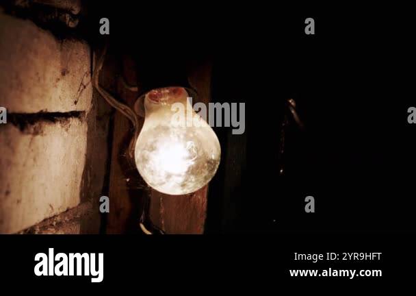 A solitary, dusty light bulb illuminates a dark corner with a cobweb ...