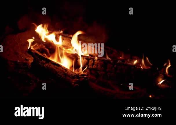 Burning logs in a campfire at night, flames and embers glowing. Warmth ...