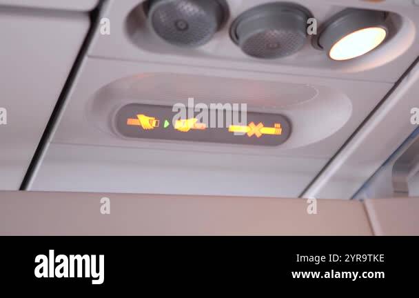 Closeup of airplane cabin controls showing illuminated seatbelt and no ...