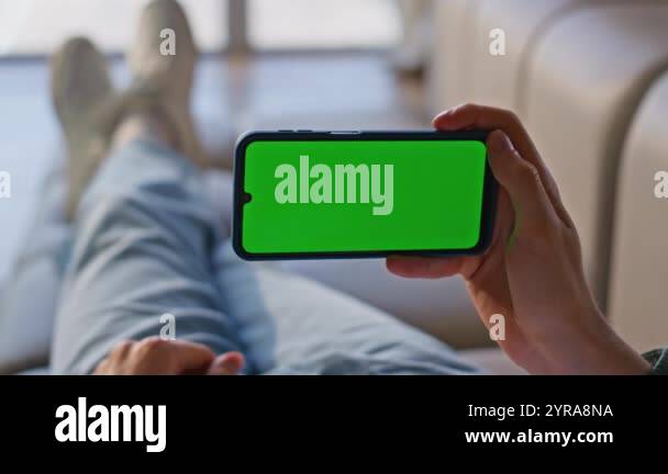 Closeup hands holding chromakey mobile phone at home. Unrecognized man ...