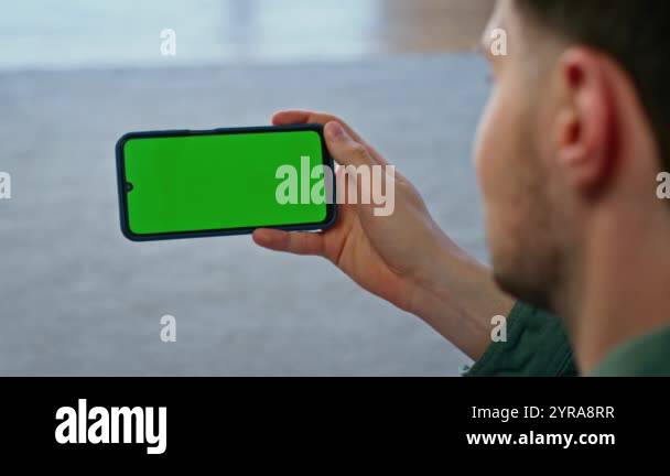Man hands holding mockup smartphone at home living room closeup. Unrecognizable guy looking on ...