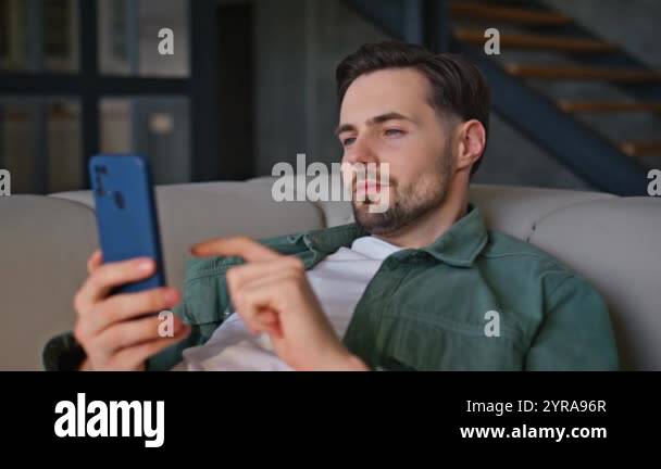 Lying guy typing smartphone couch looking screen at house environment ...