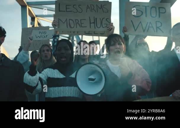 Young brave woman with megaphone in anti-war protest with diverse group ...
