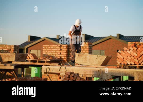 A professional construction worker in safety gear carefully places ...