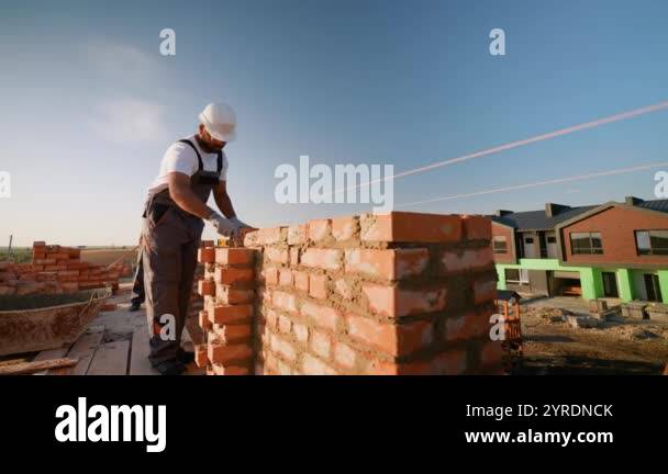 Two dedicated builders work meticulously, laying bricks to construct a ...