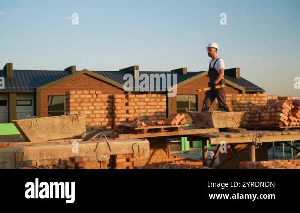 A construction worker carries a level while walking on a site building ...