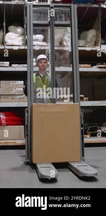 Warehouse employee using a forklift to transport a large box of goods ...