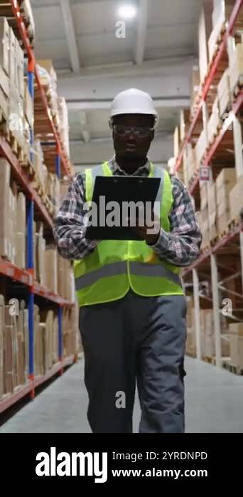 African American warehouse employee in a hard hat and safety vest ...