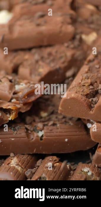 Grated chocolate pouring on rotating nut chocolate bars, vertical slow ...