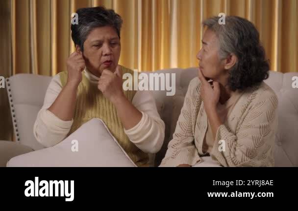 Footage Locked medium shot, Asian senior woman consoles her distressed friend with short hair ...