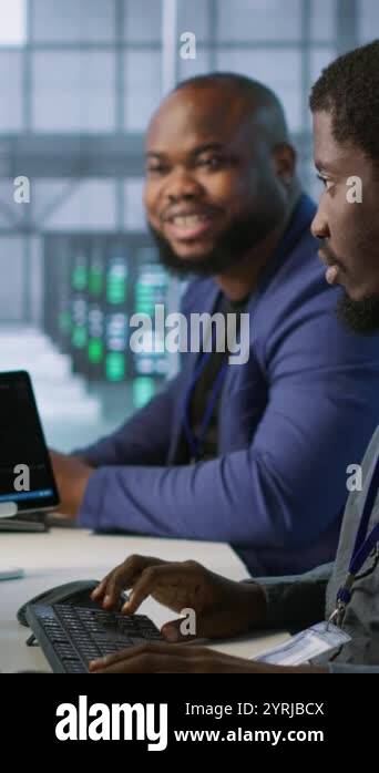 Vertical video Cheerful coworkers in data center implementing AI predictive maintenance systems ...