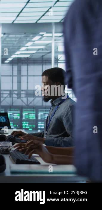 Vertical video Admin arriving in server room, starting work on ...