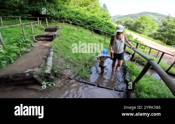 Walking barefoot through mud and water in a sensory park to enjoy nature and the senses, Black ...