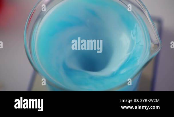 Liquid reagents create whirlpool in transparent beaker. Interaction of ...